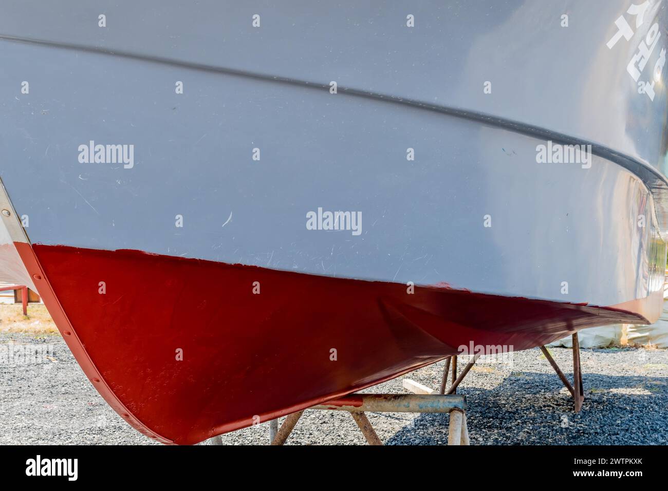 The red and gray hull of a ship in dry dock stands ready for ...