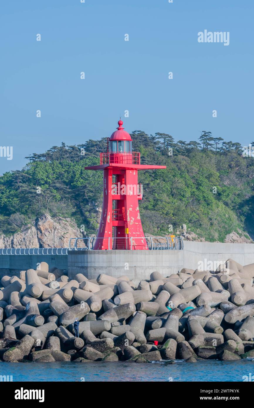 Bright red lighthouse on a jetty with tetrapod wave breakers, in Sinjin ...
