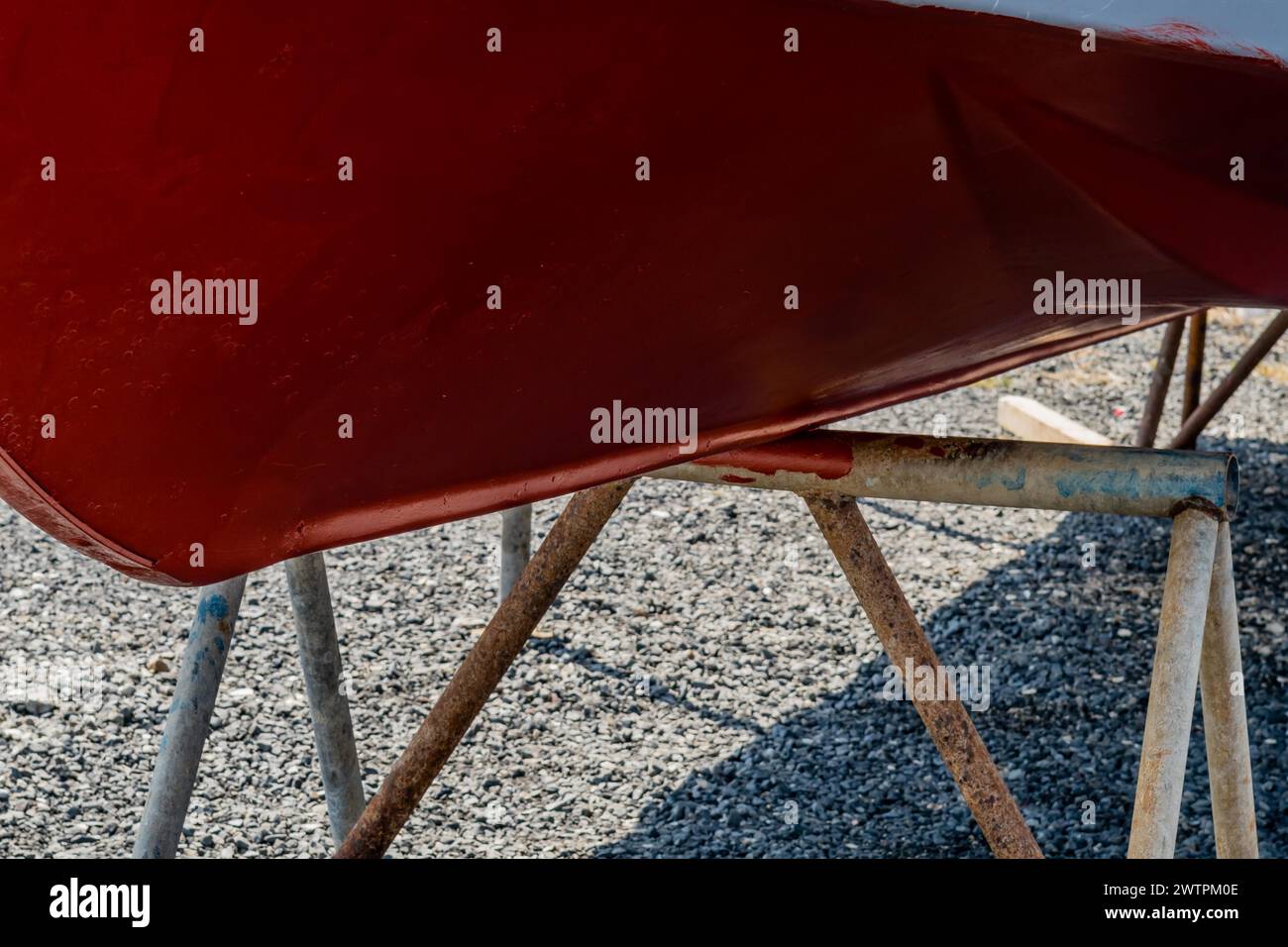 Close-up of a boat hull supported by metal stands, highlighting red ...