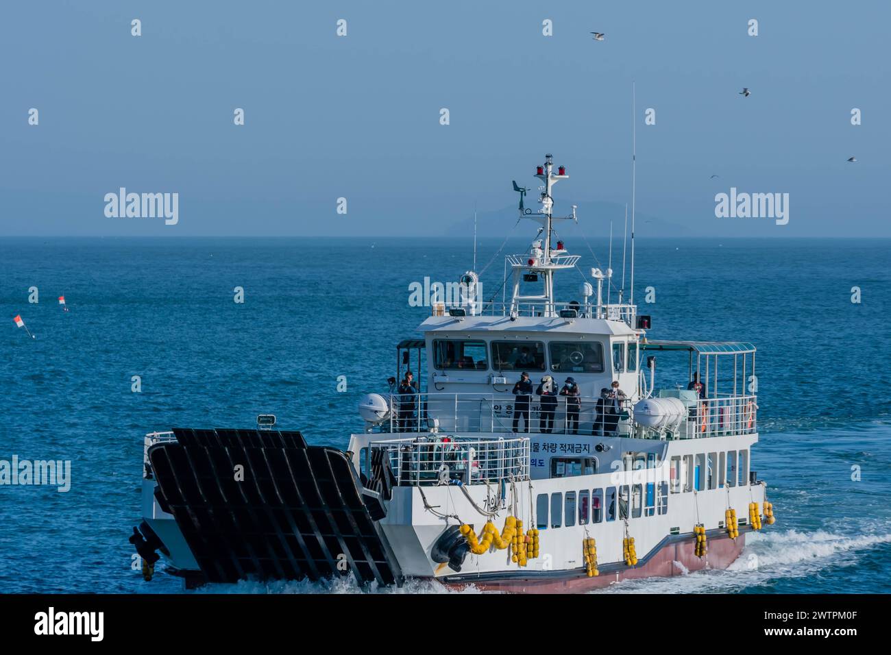 A ferry boat cruising on blue waters leaving behind a white wake, in ...