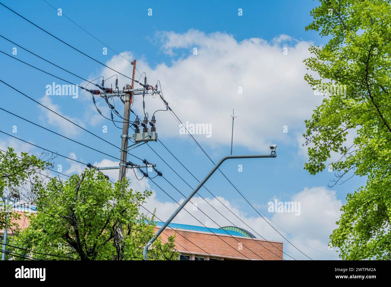 Closed circuit camera mounted on metal pole beside power lines with ...