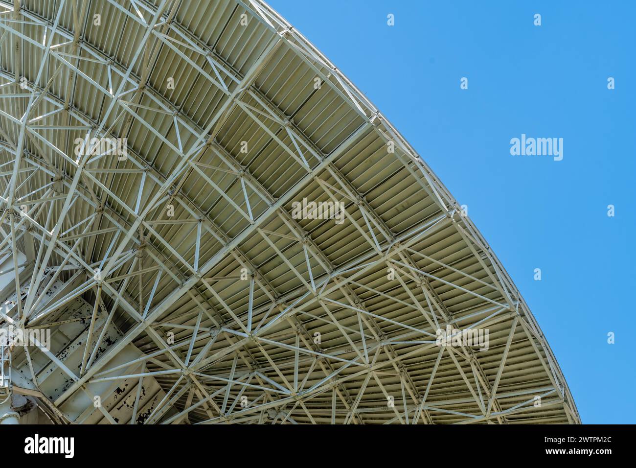 Underside view of a massive satellite dish, highlighting its structural ...