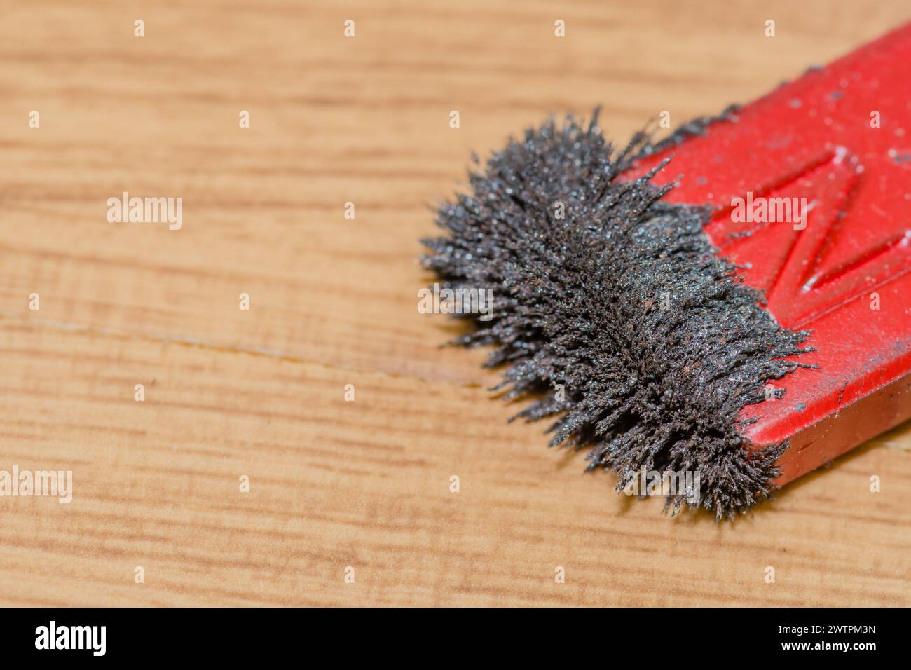 Red magnet attracting iron filings, illustrating a magnetic field in a ...