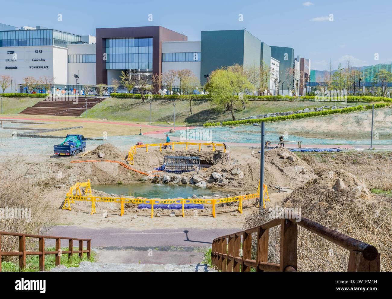 Construction site with heavy machinery, barriers, and a dirt pile near ...