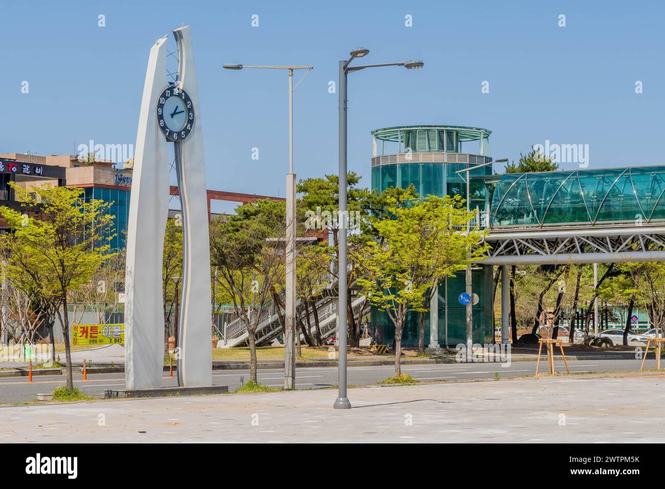 A modern outdoor clock in a public space with clear blue skies and a ...