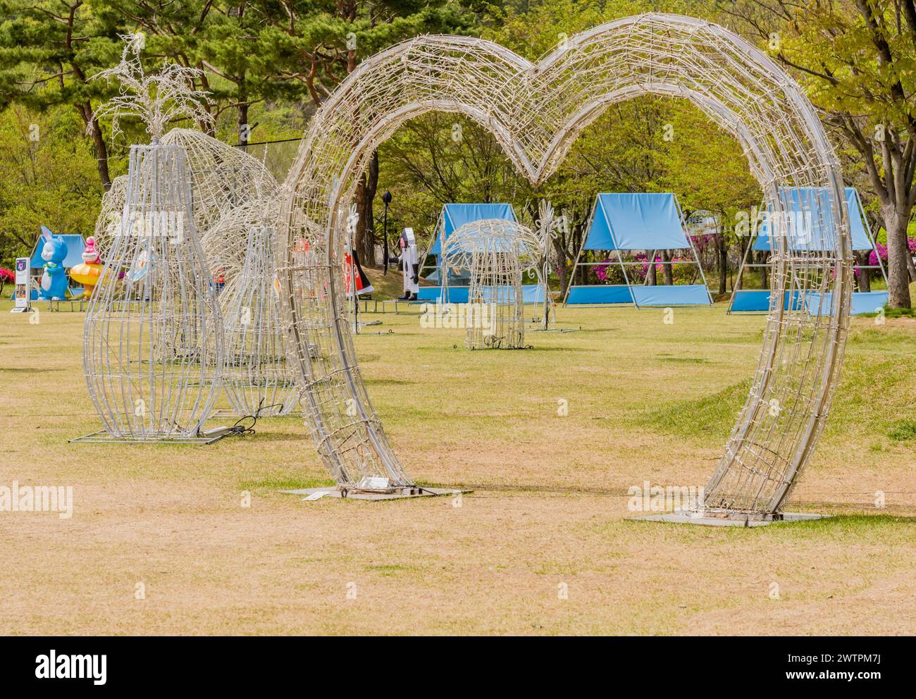 A park with wire sculptures, including a heart shape, and tents in the ...