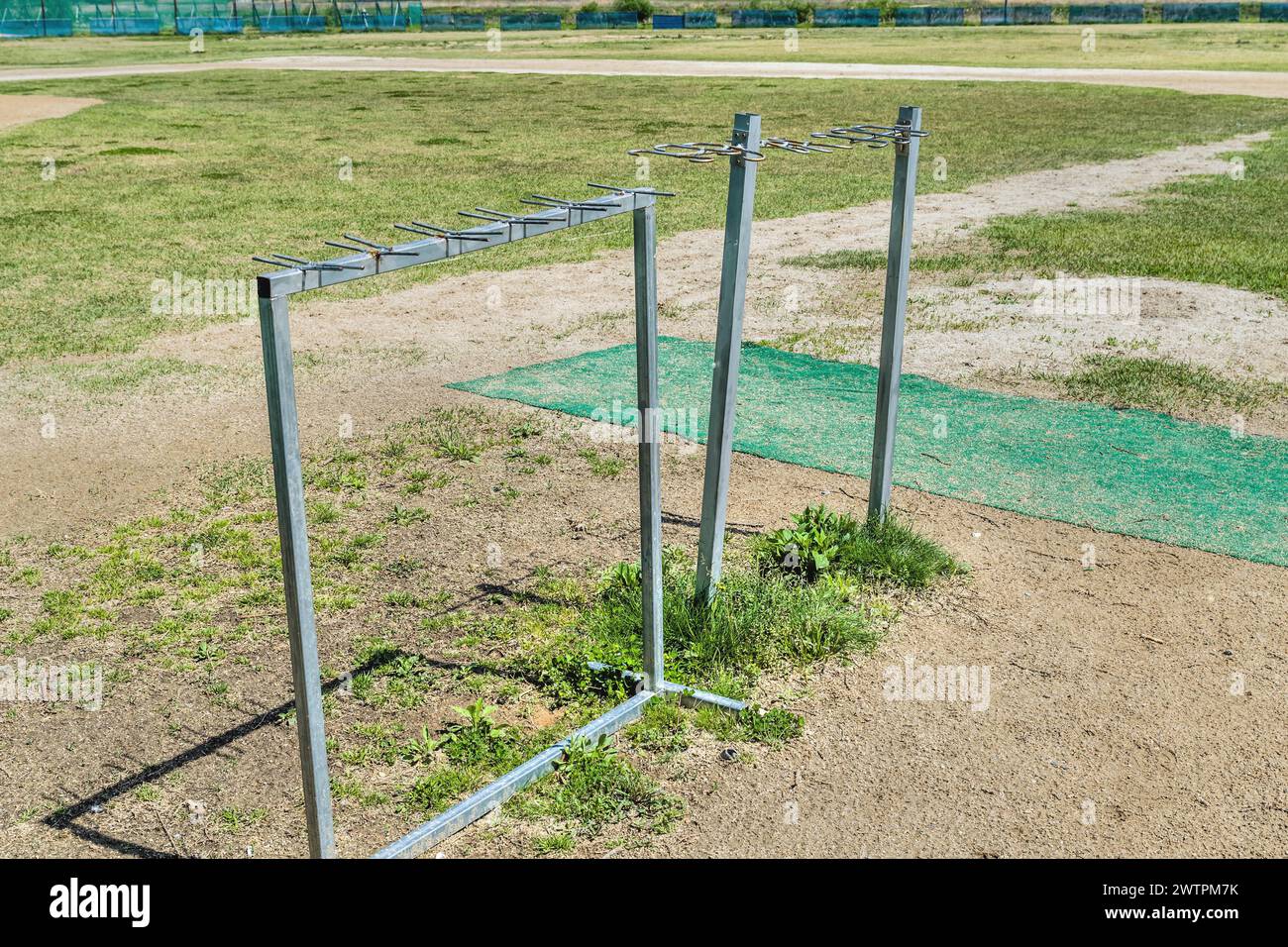 Metal baseball practice equipment on a grass field with a clear sky, in ...