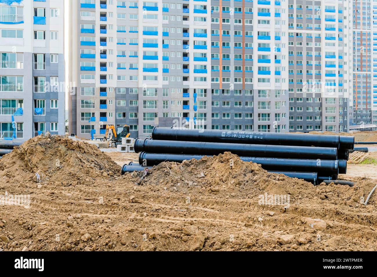 Building site with stacks of construction pipes and earthworks in front ...