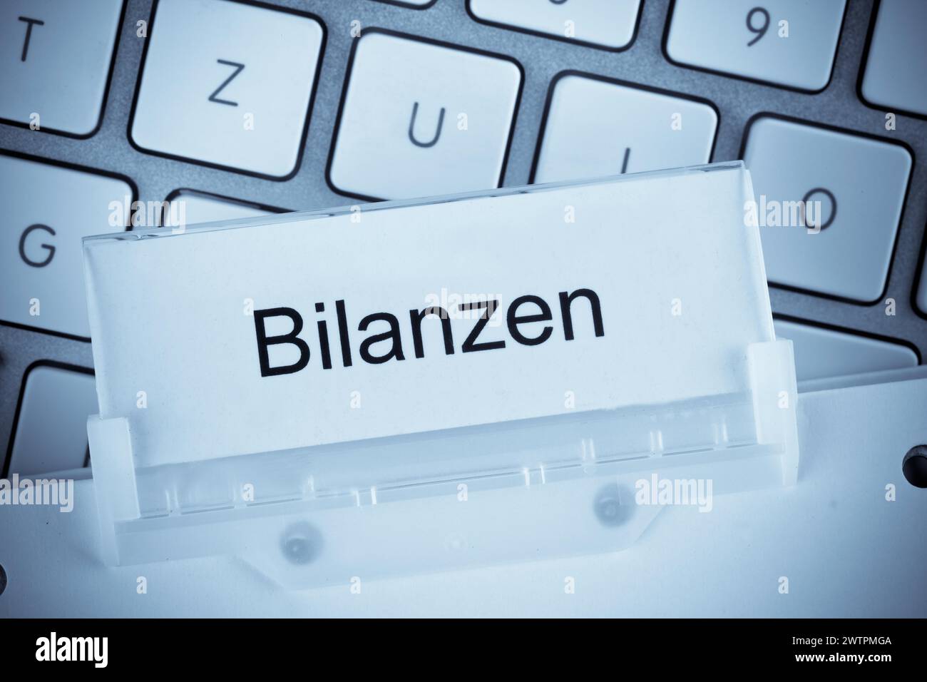 The folder of a hanging file in front of a computer keyboard on the ...