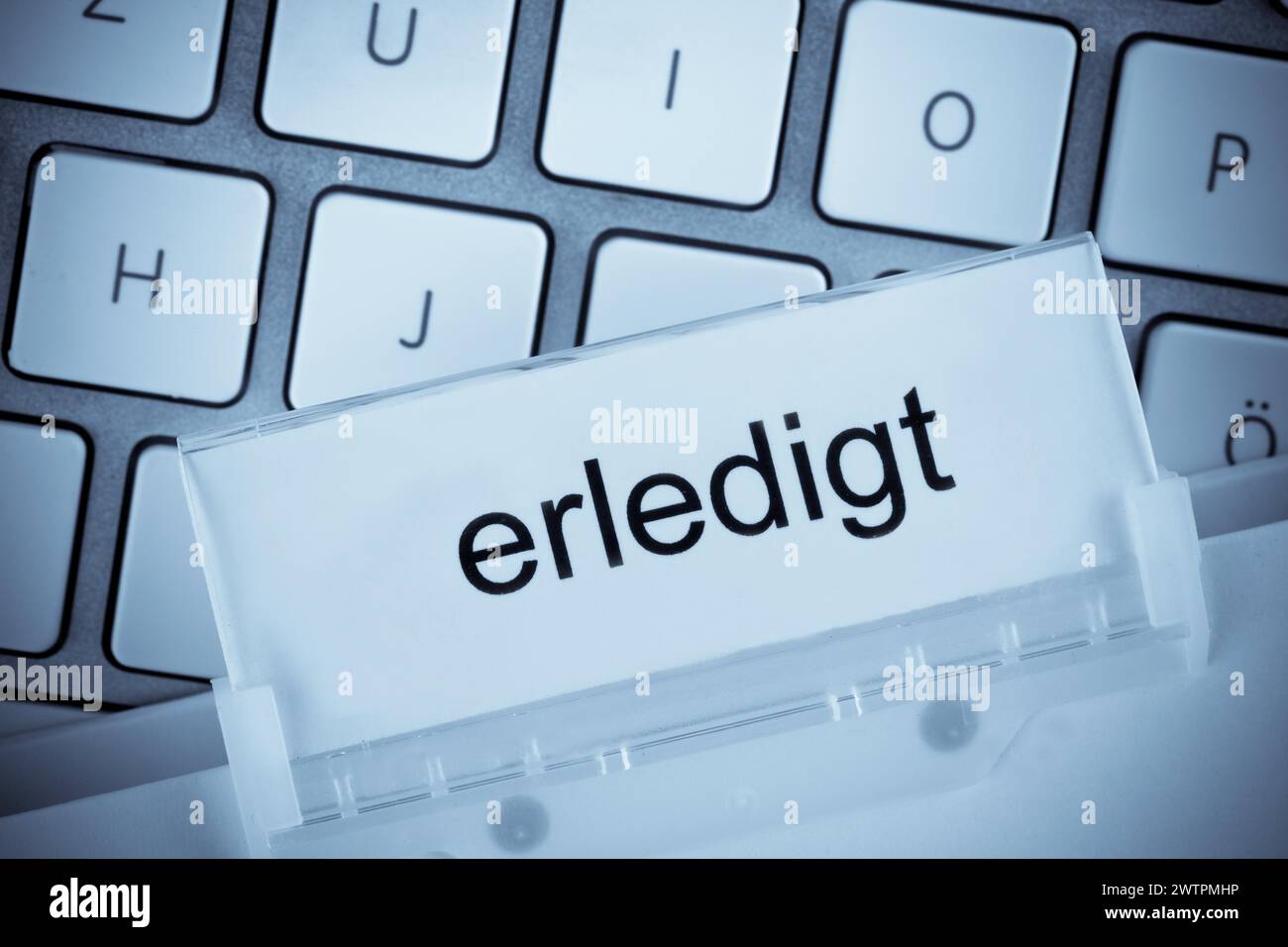The folder of a hanging file in front of a computer keyboard on the ...