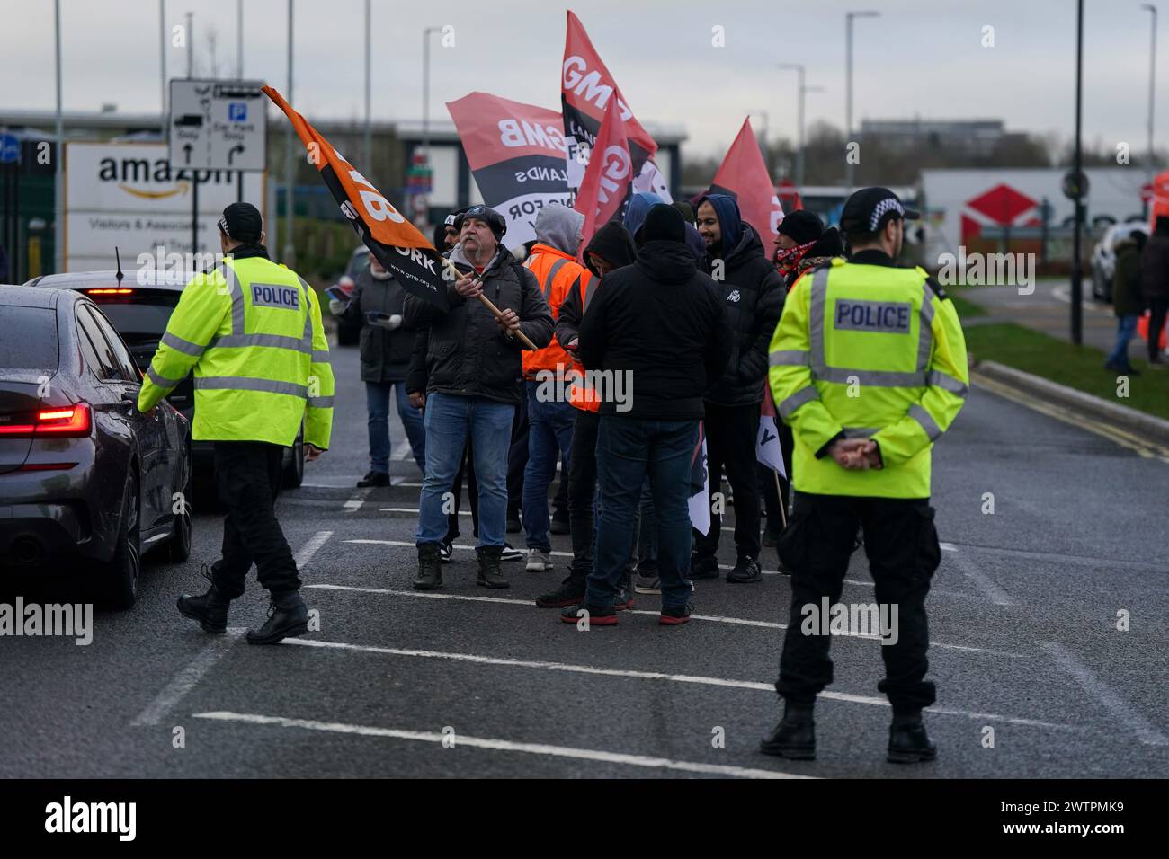 Police officers stand by Amazon staff members on a GMB union picket ...