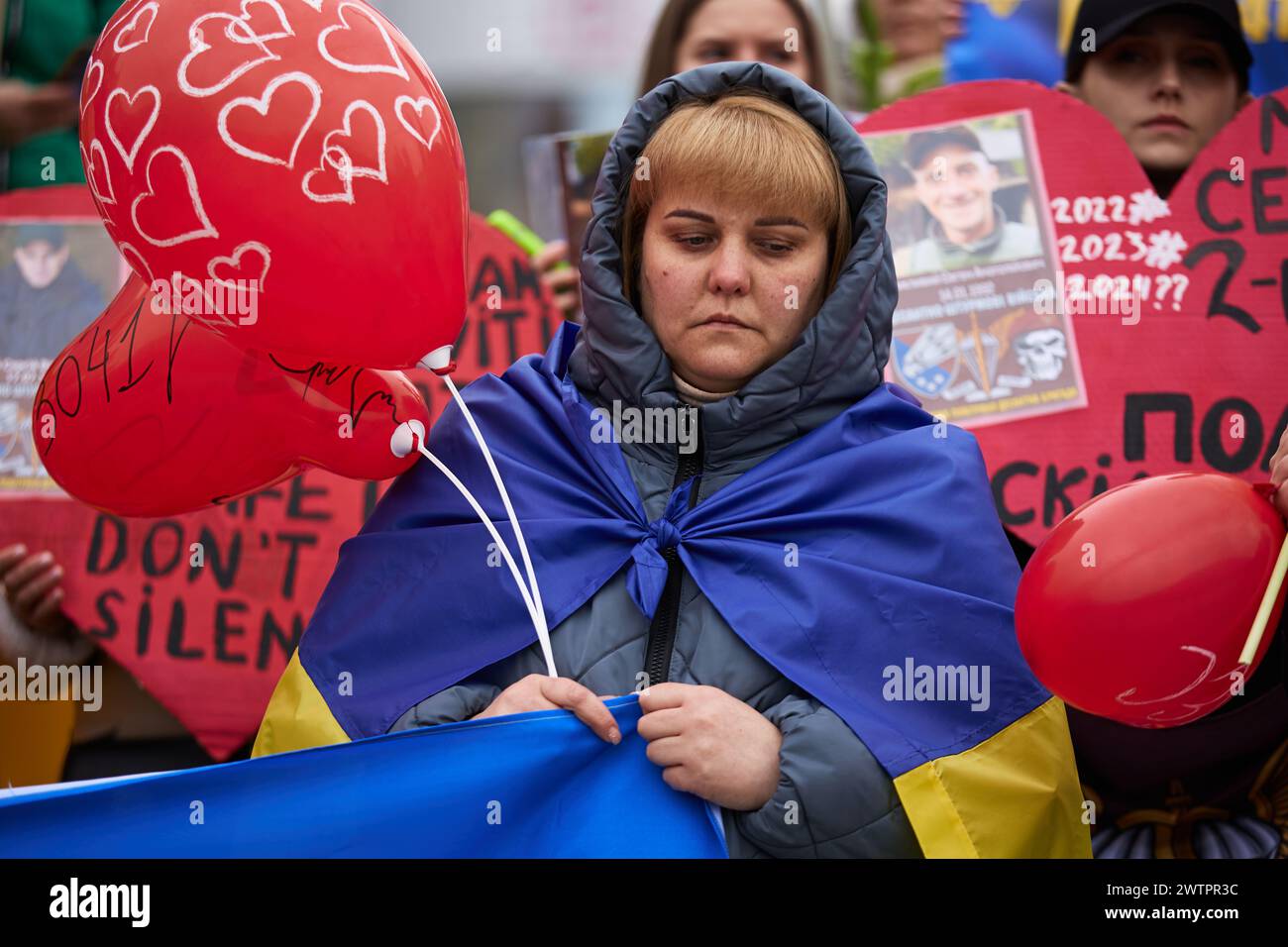 Sad woman wearing Ukrainian national flag on shoulders at the public ...