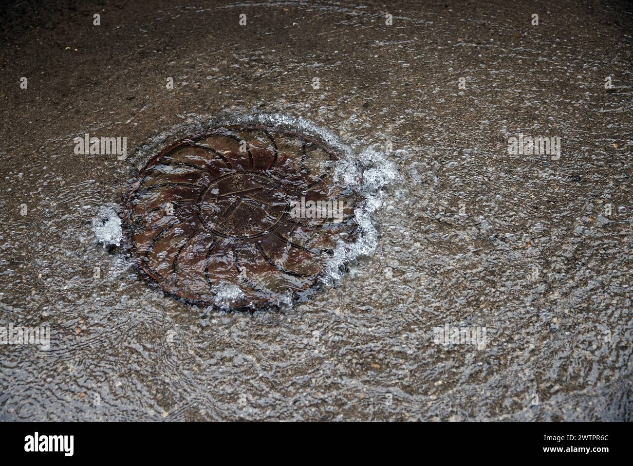 Water pipe burst, water Water flows out of the manhole onto the asphalt ...