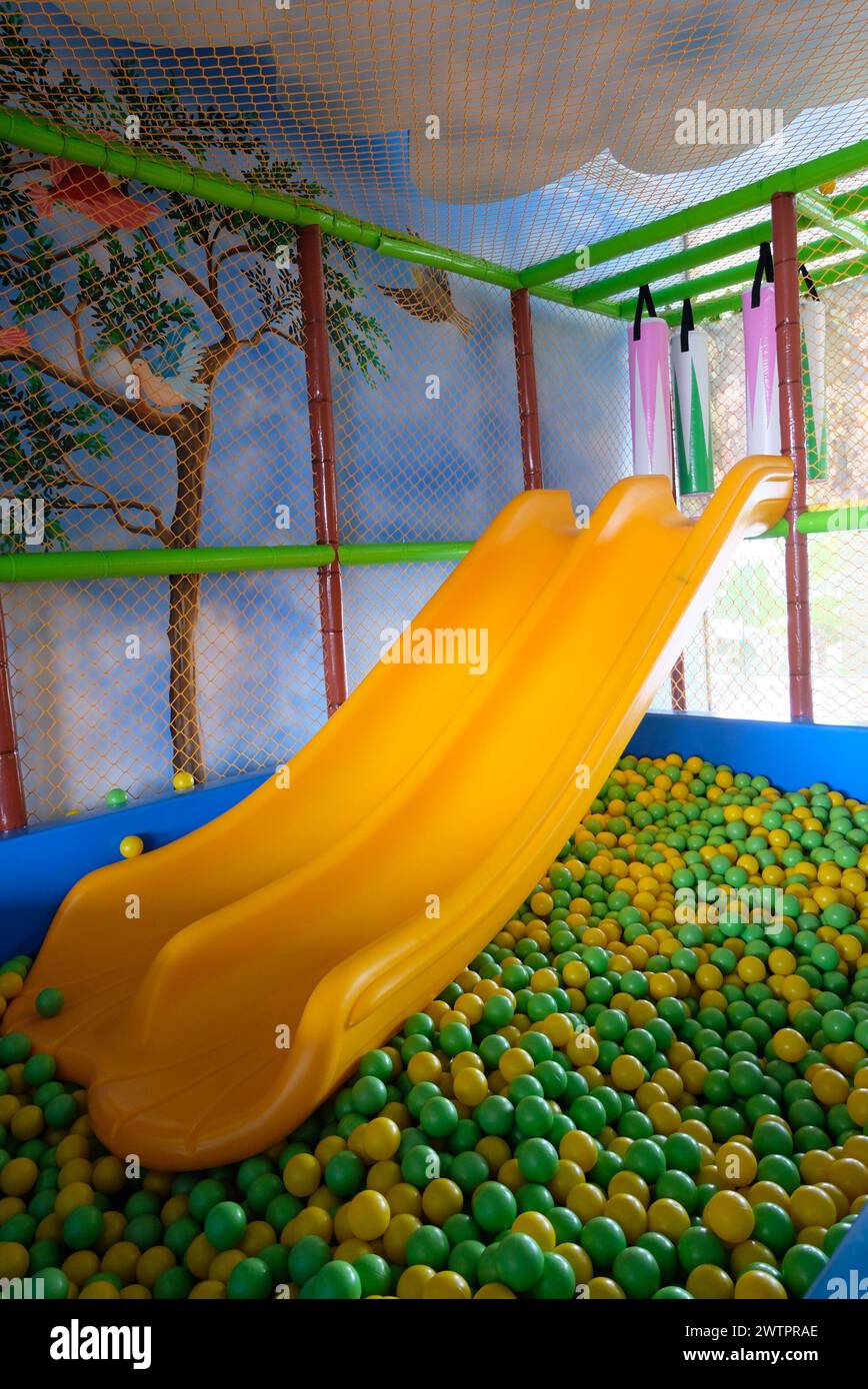 Yellow slide at indoor playground against colourful plastic balls ...