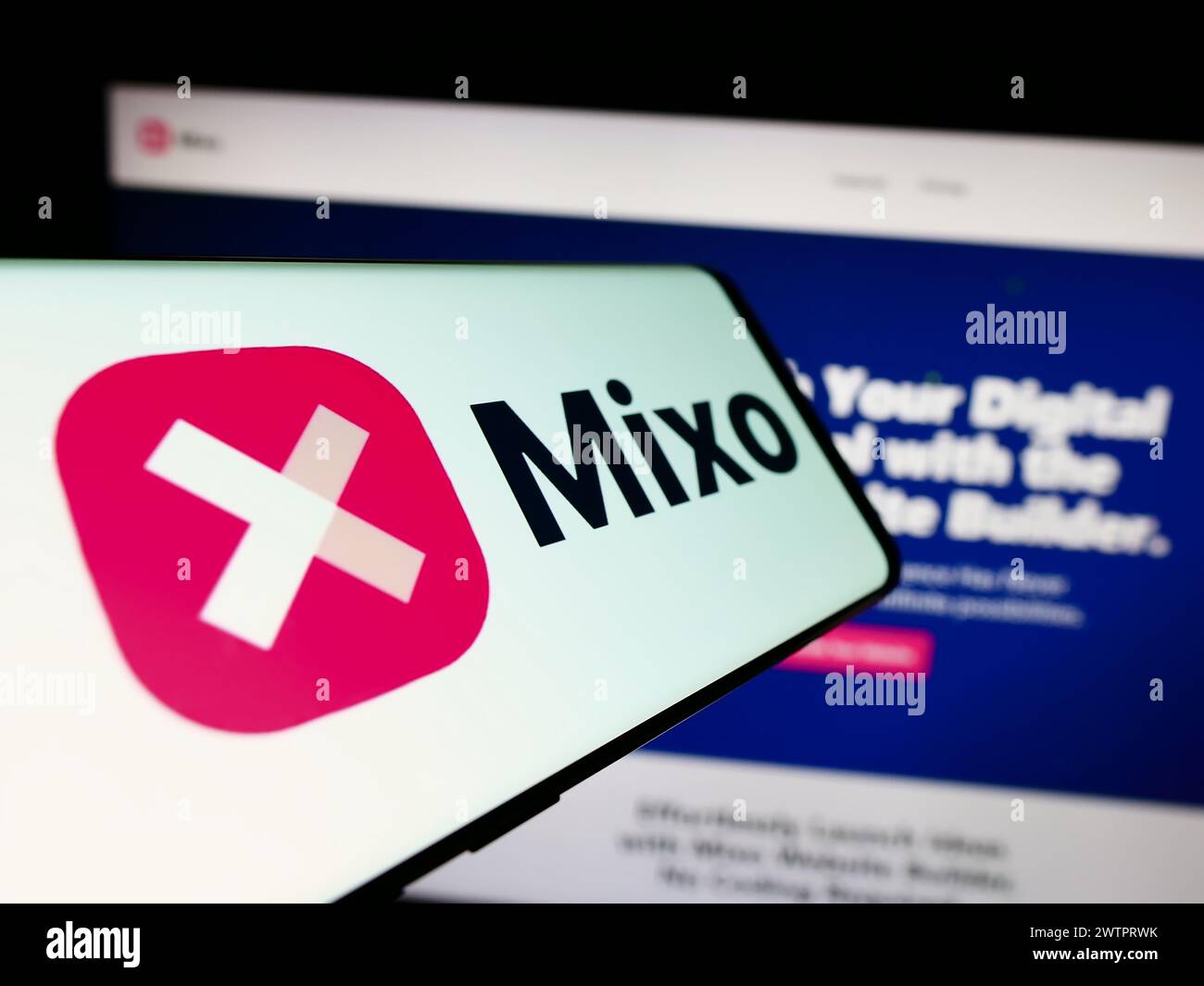 Smartphone with logo of AI website building company Mixo in front of business website. Focus on ...