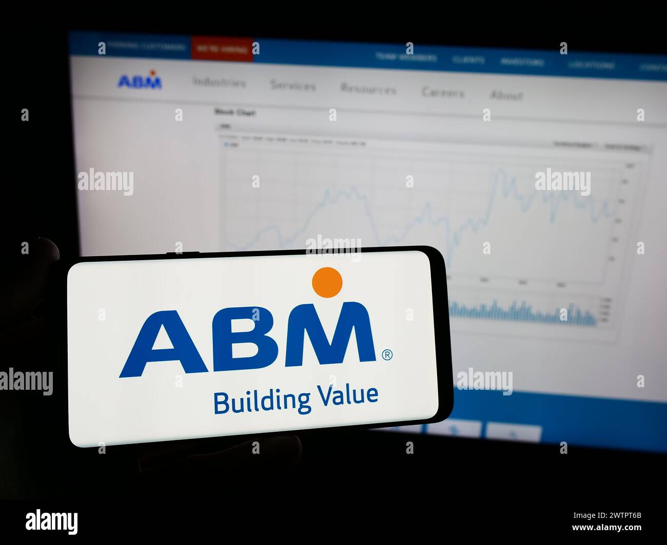 Person holding mobile phone with logo of American facility management company ABM Industries Inc ...