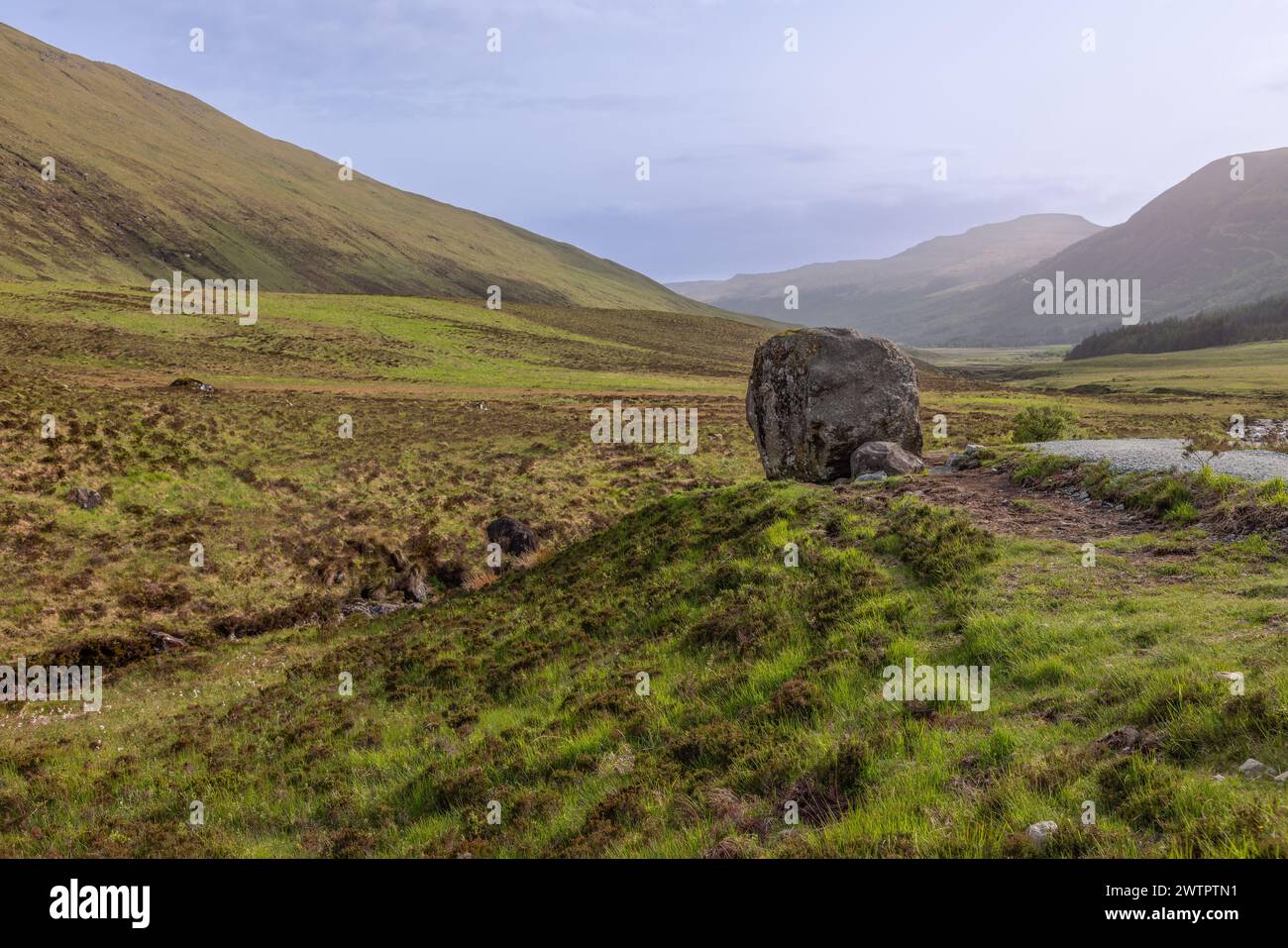 A solitary boulder stands in the foreground of a sweeping valley on the ...