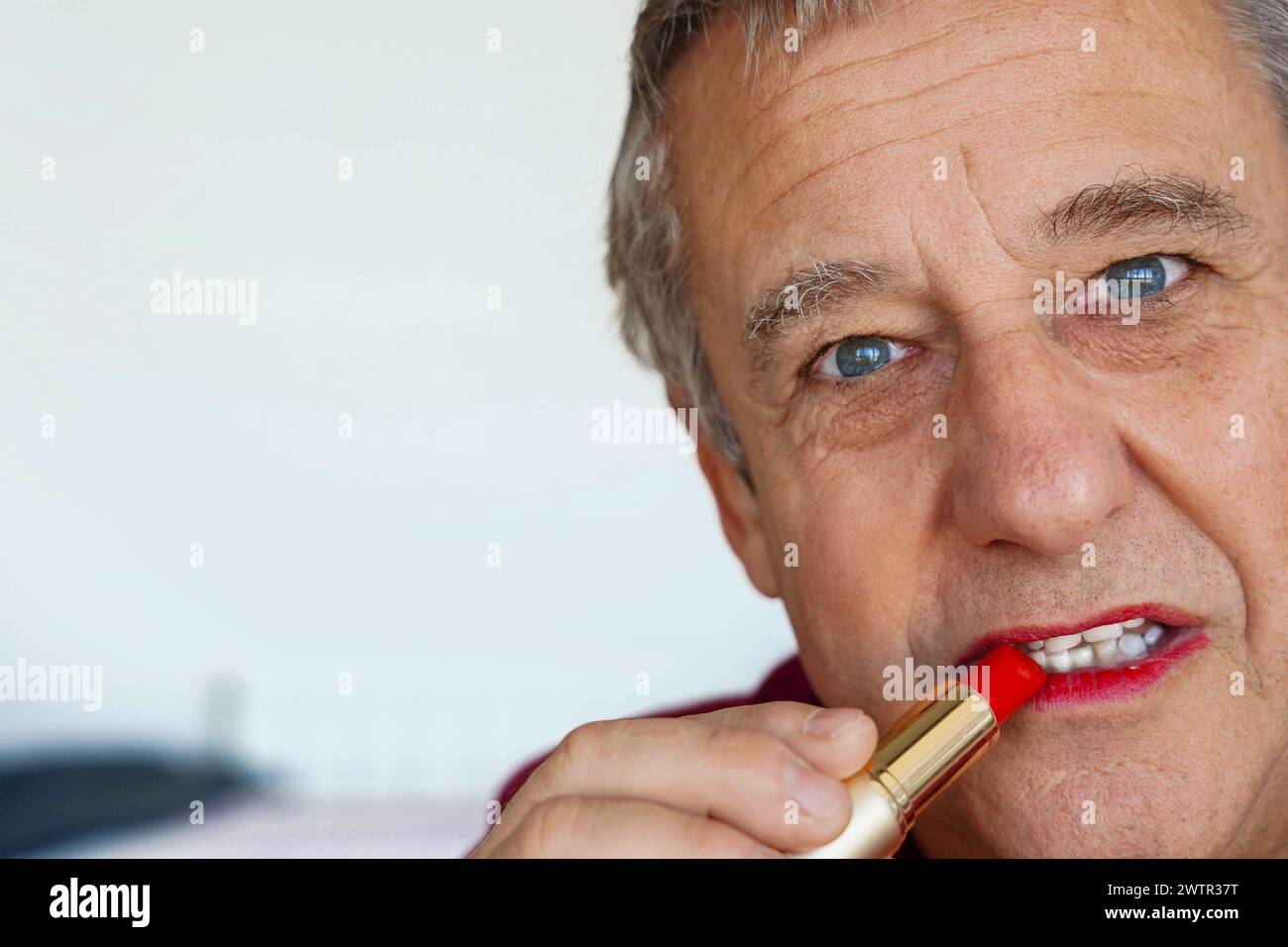 Portrait of mature man putting on lipstick. A gay man putting on makeup ...