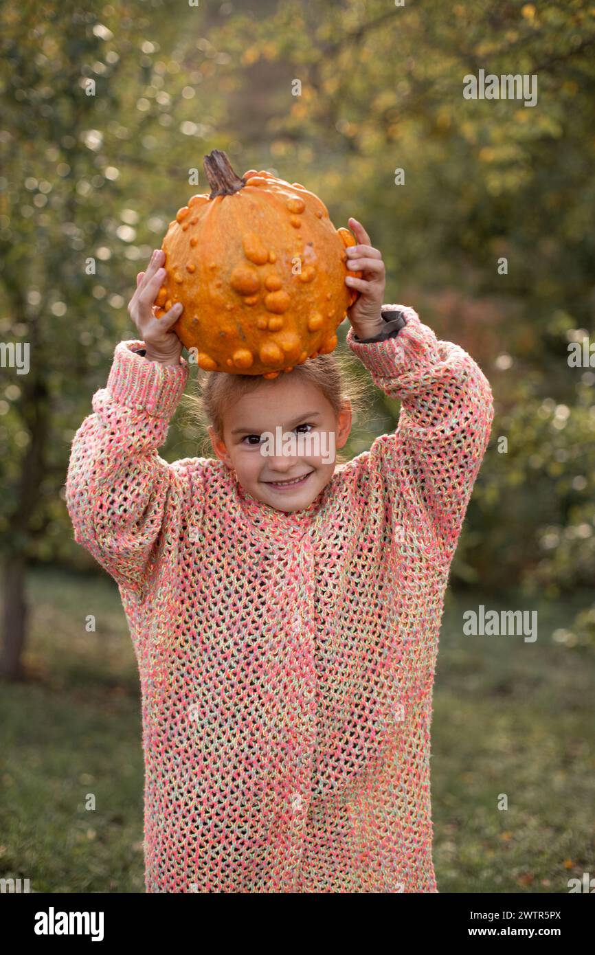 Happy smilling child girl in a knitted sweater is holding in hands ugly ...