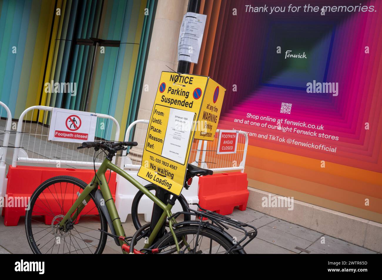 A bike is locked to a post where a parking suspended notice is attached ...