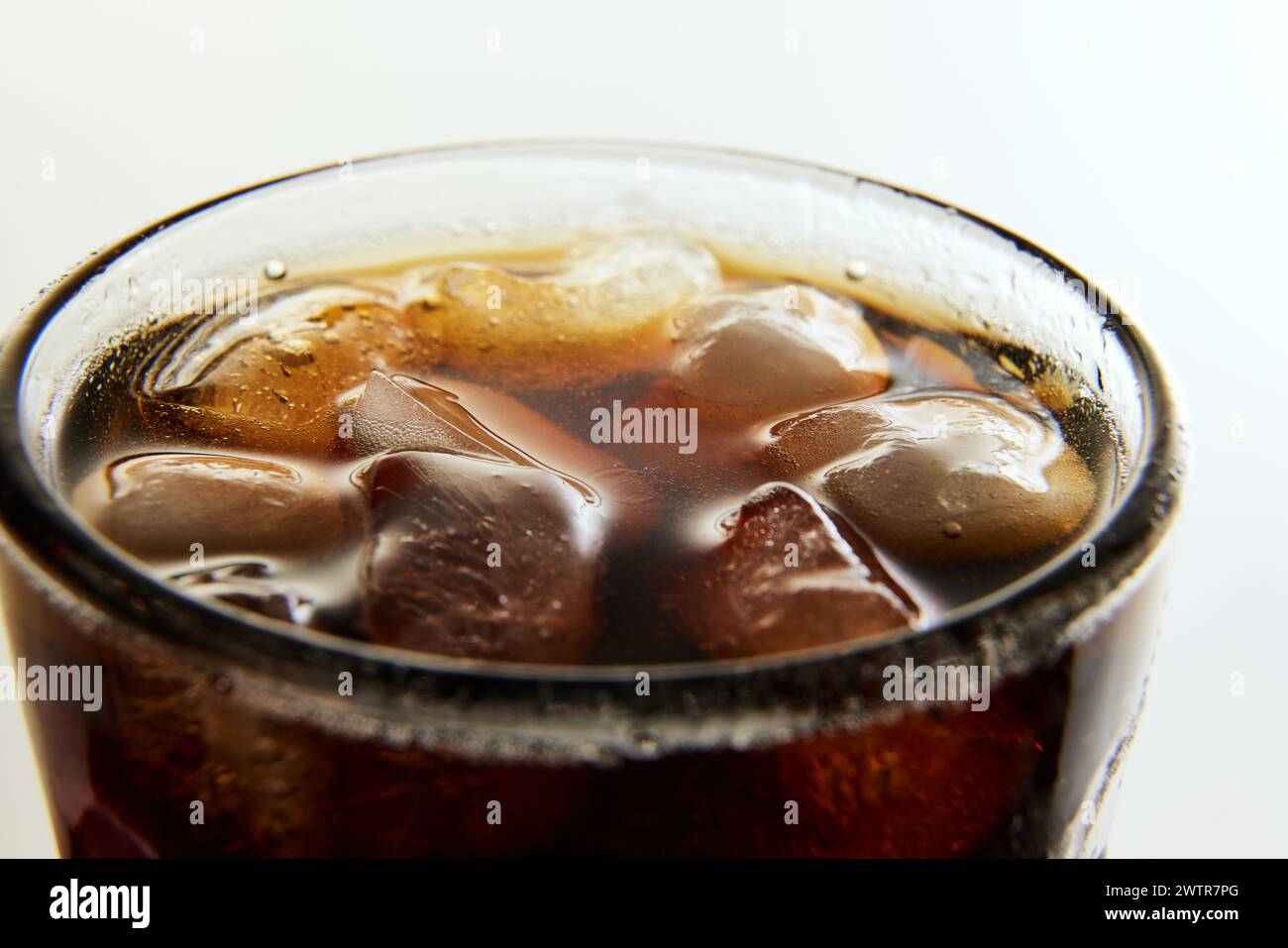 Glass wit foamy drink, soda water, coke, dark beer with ice cubes ...