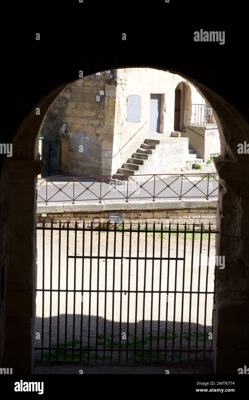 Building with staircase seen through an arch of the Arles Amphitheatre ...