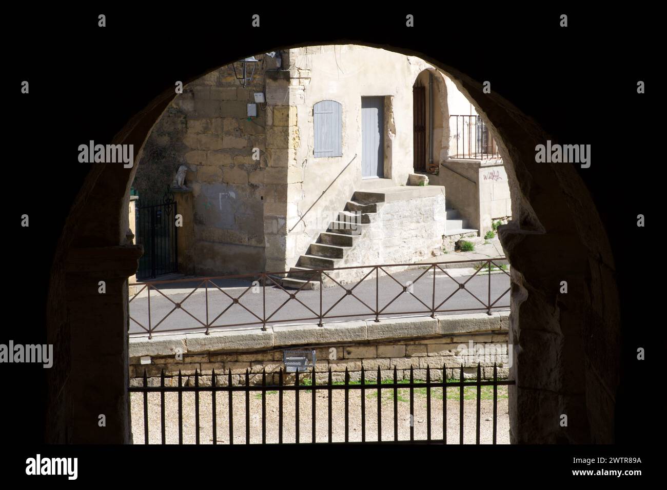 Building with staircase seen through an arch of the Arles Amphitheatre ...