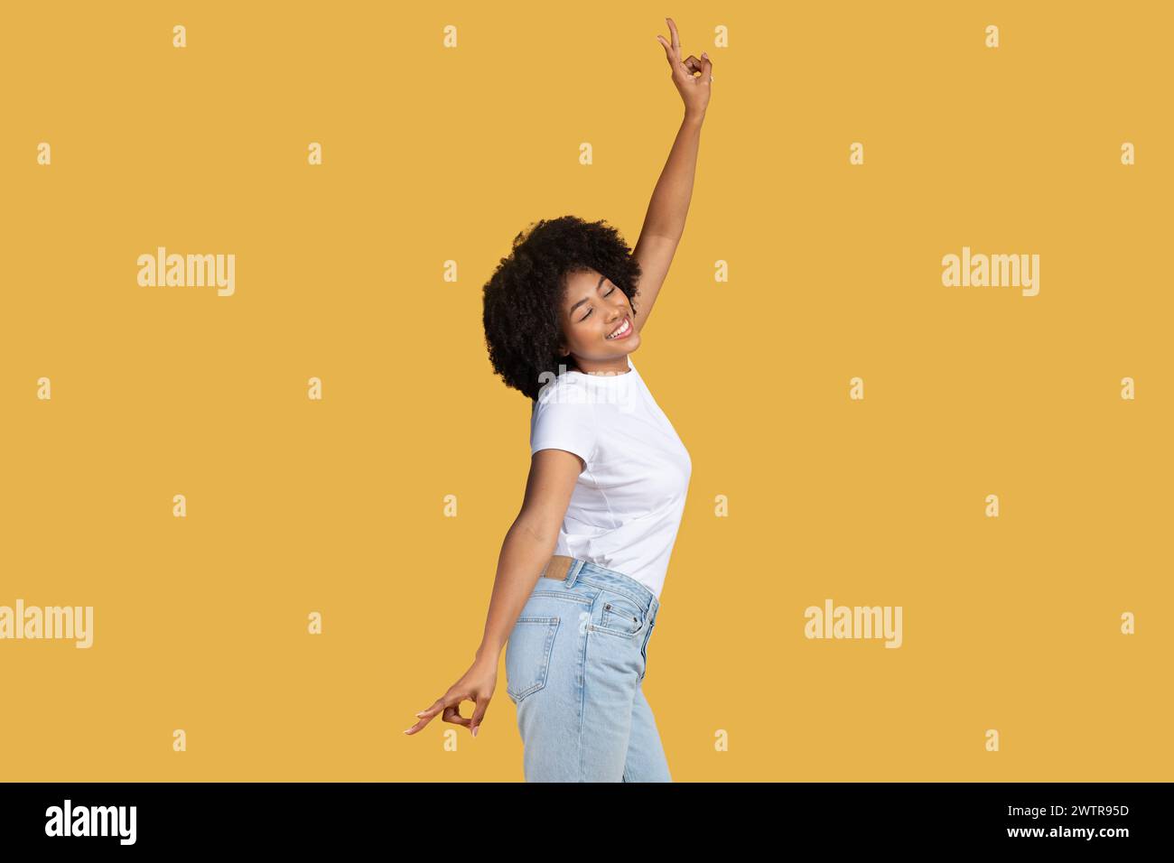 Joyful African American woman dancing and pointing upwards with a ...