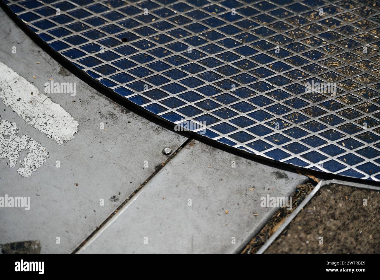 A close-up of a metallic grate against concrete, textures and patterns ...