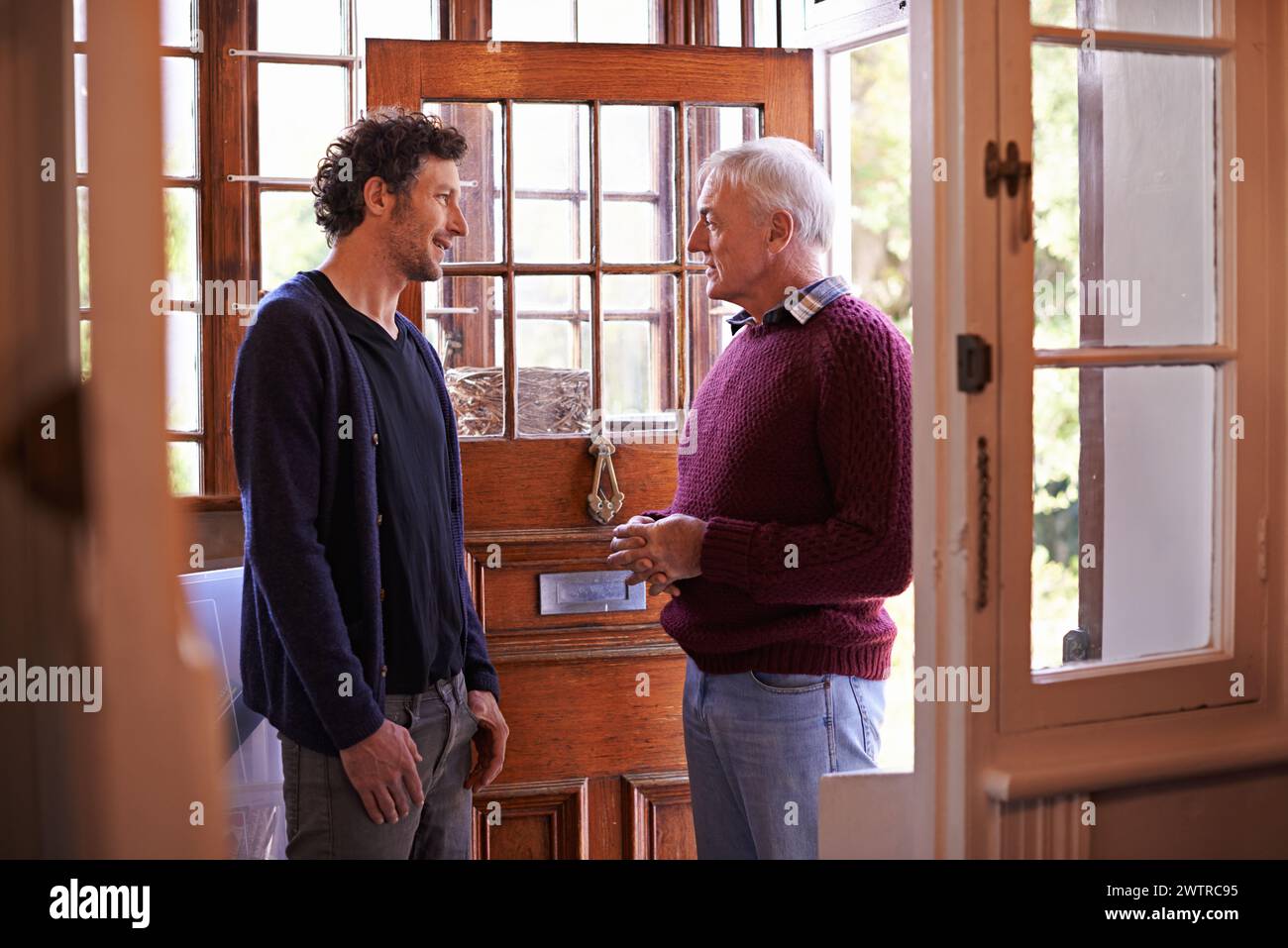 Son, senior dad and talking in home by front door with advice, chat and ...