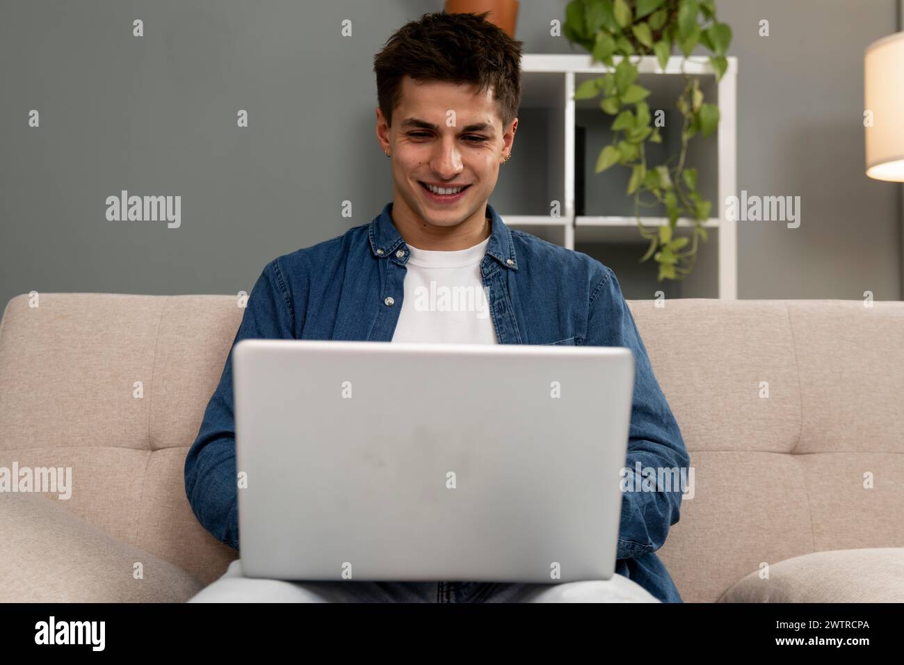 Handsome relaxed male student working with laptop while sitting on the ...