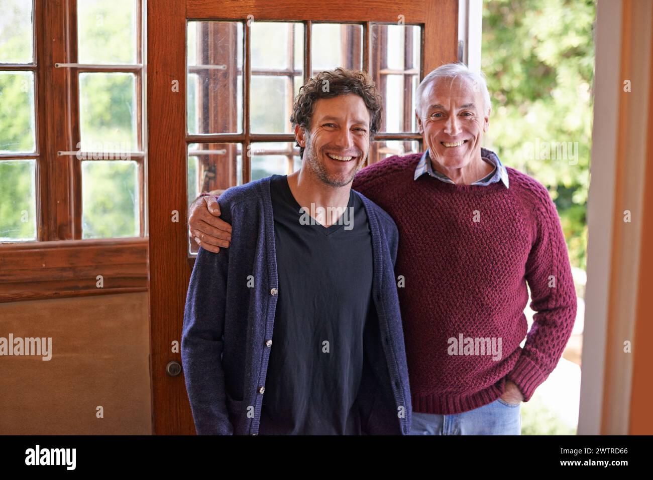 Son, elderly father and portrait in home by front door with hug, smile ...