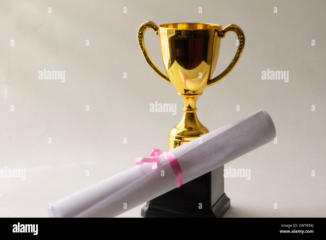 Golden trophy and diploma displayed on desk next to rolled paper Stock ...