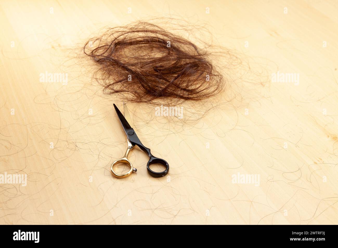 Scissors on wood table with hair strand in background Stock Photo - Alamy