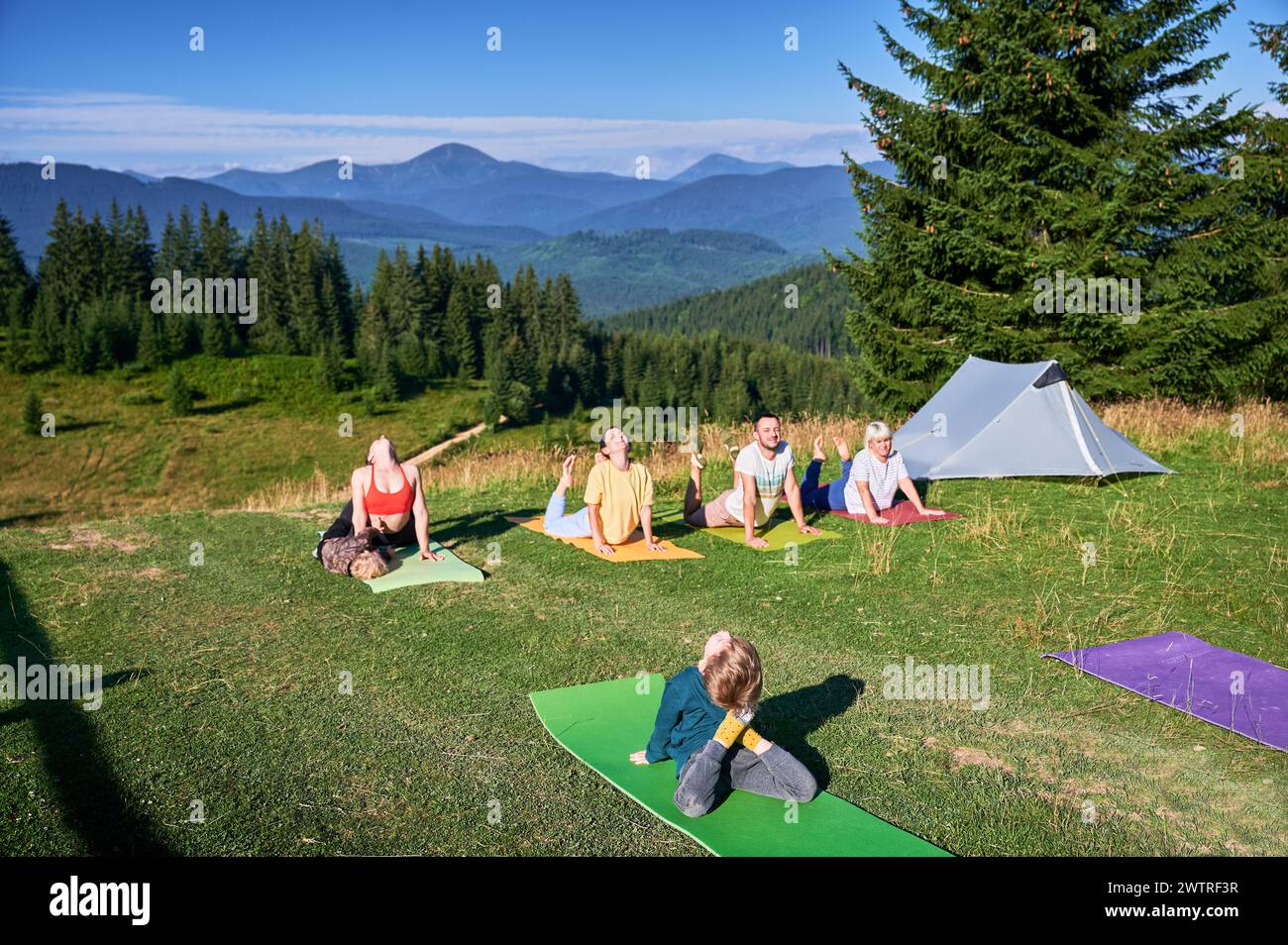 Group of people doing yoga pose outdoor in camping in the mountains ...