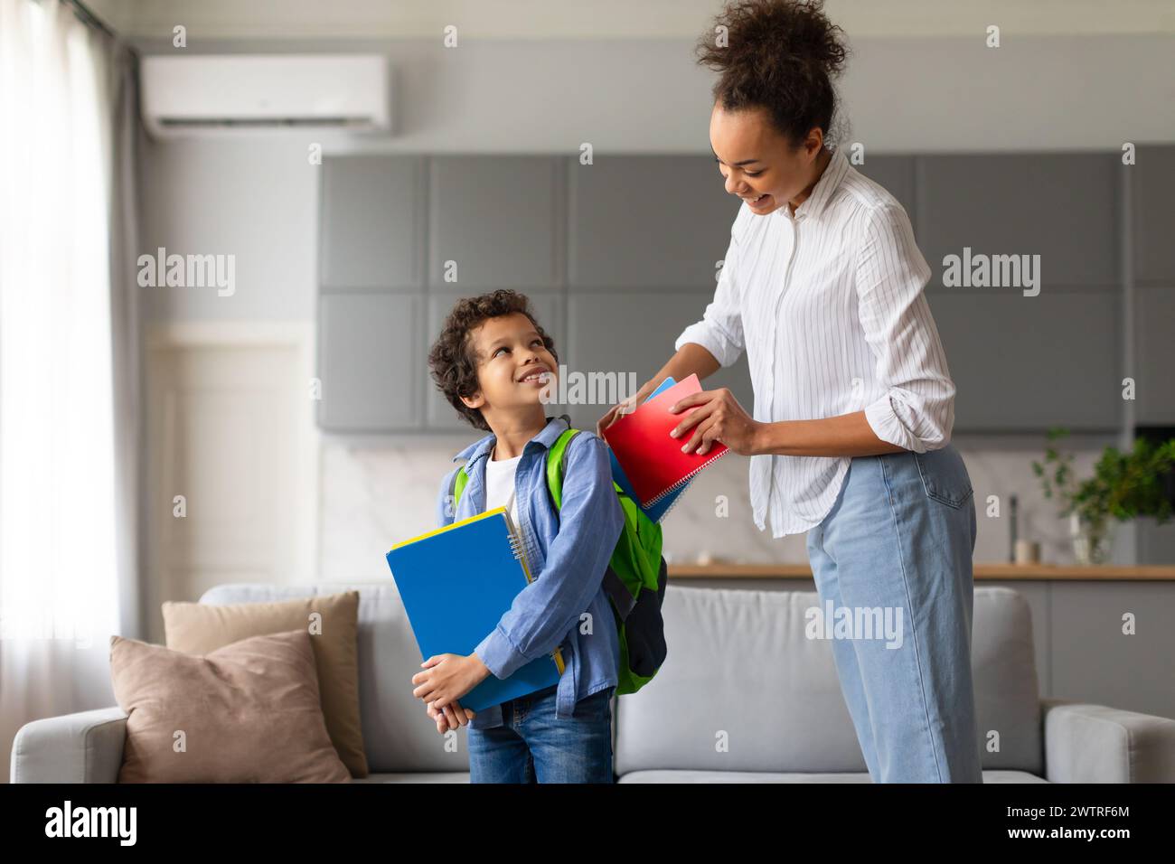 Mother preparing son for school with backpack Stock Photo - Alamy