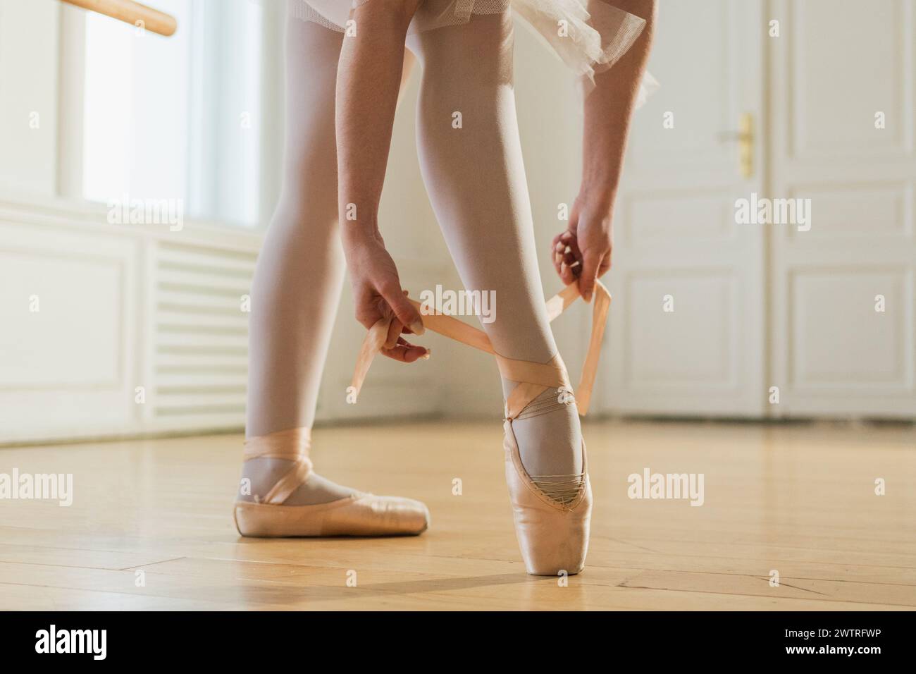 Ballerina puts on pointe shoes on leg in dance class. Classical ballet ...