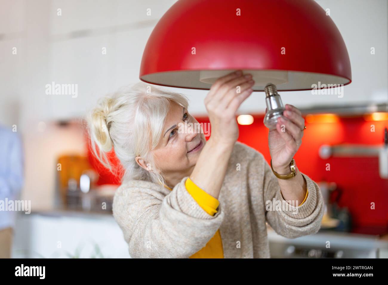 Senior woman changing light bulb in her home Stock Photo - Alamy