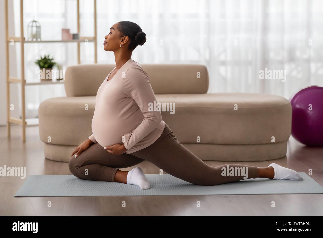 Pregnant african american woman stretching legs training at home Stock ...