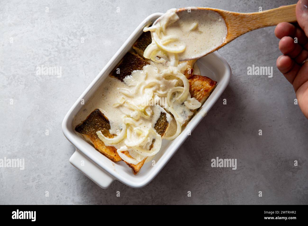 Baking dish with roasted whitefish fillet on kitchen counter. Hand ...
