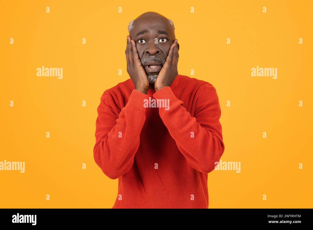 Shocked senior black man with hands on cheeks and wide eyes, wearing a ...