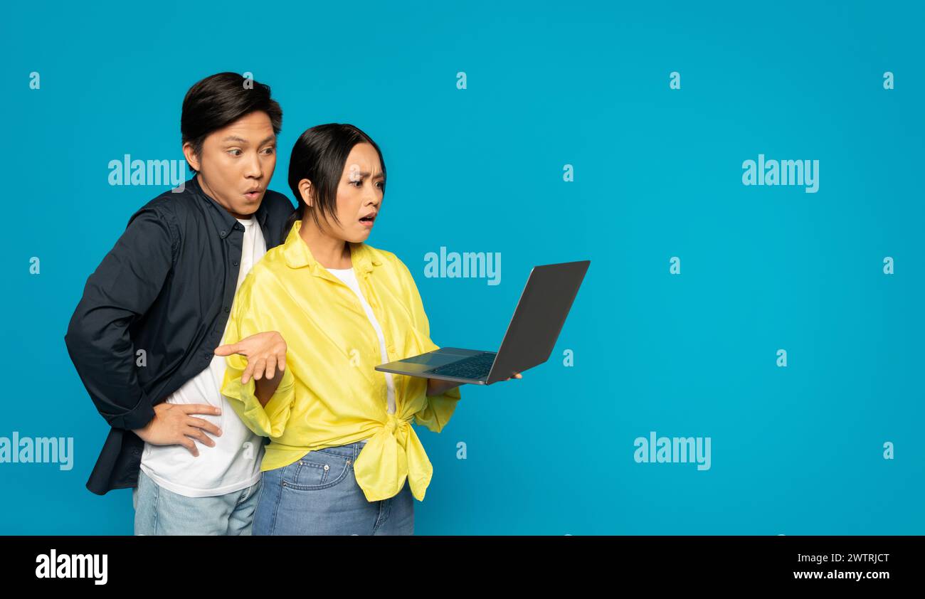 Shocked Asian couple looking at a laptop screen with surprised ...