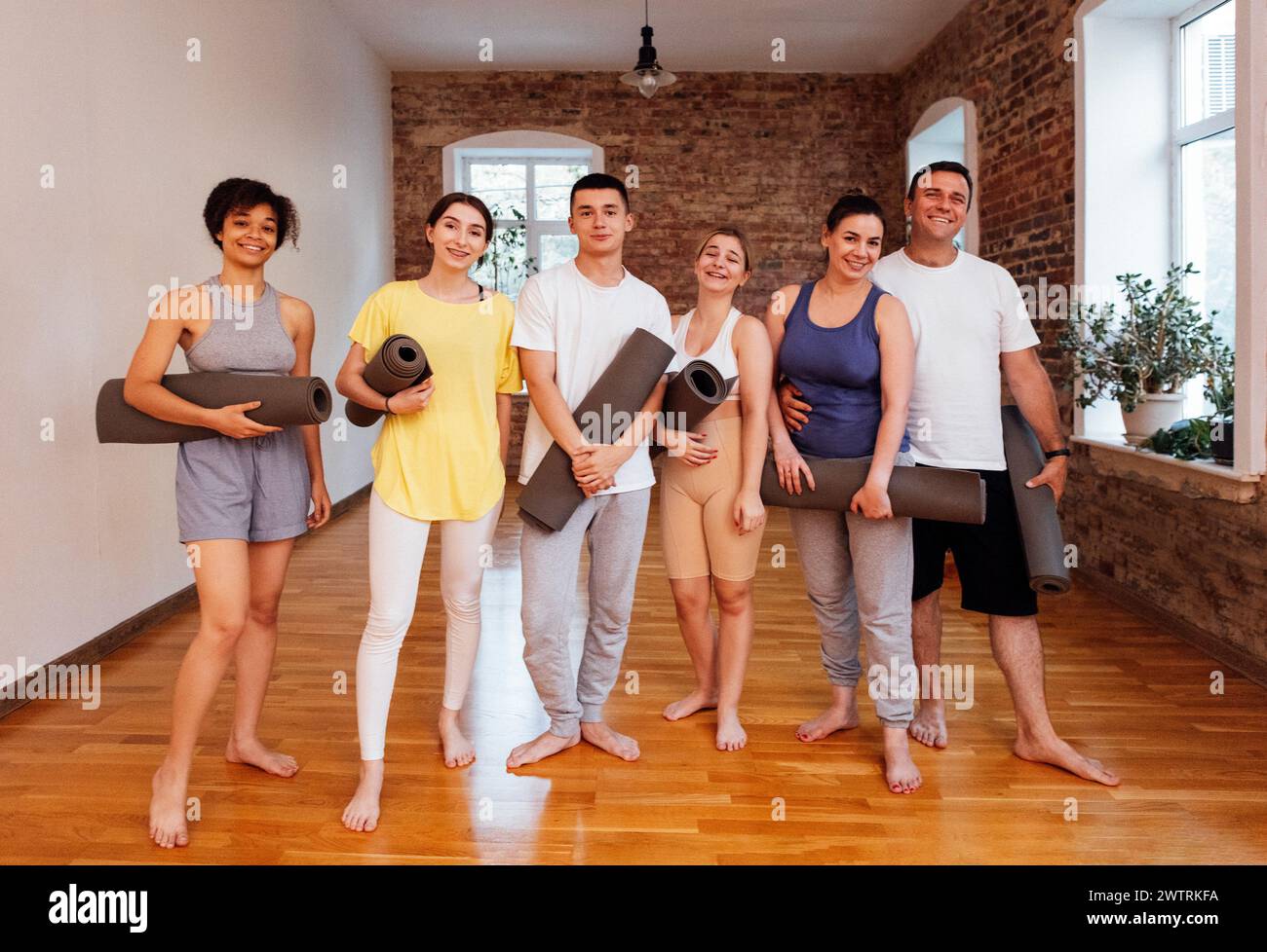 Multiracial smiling people stand with mats before yoga classes at ...