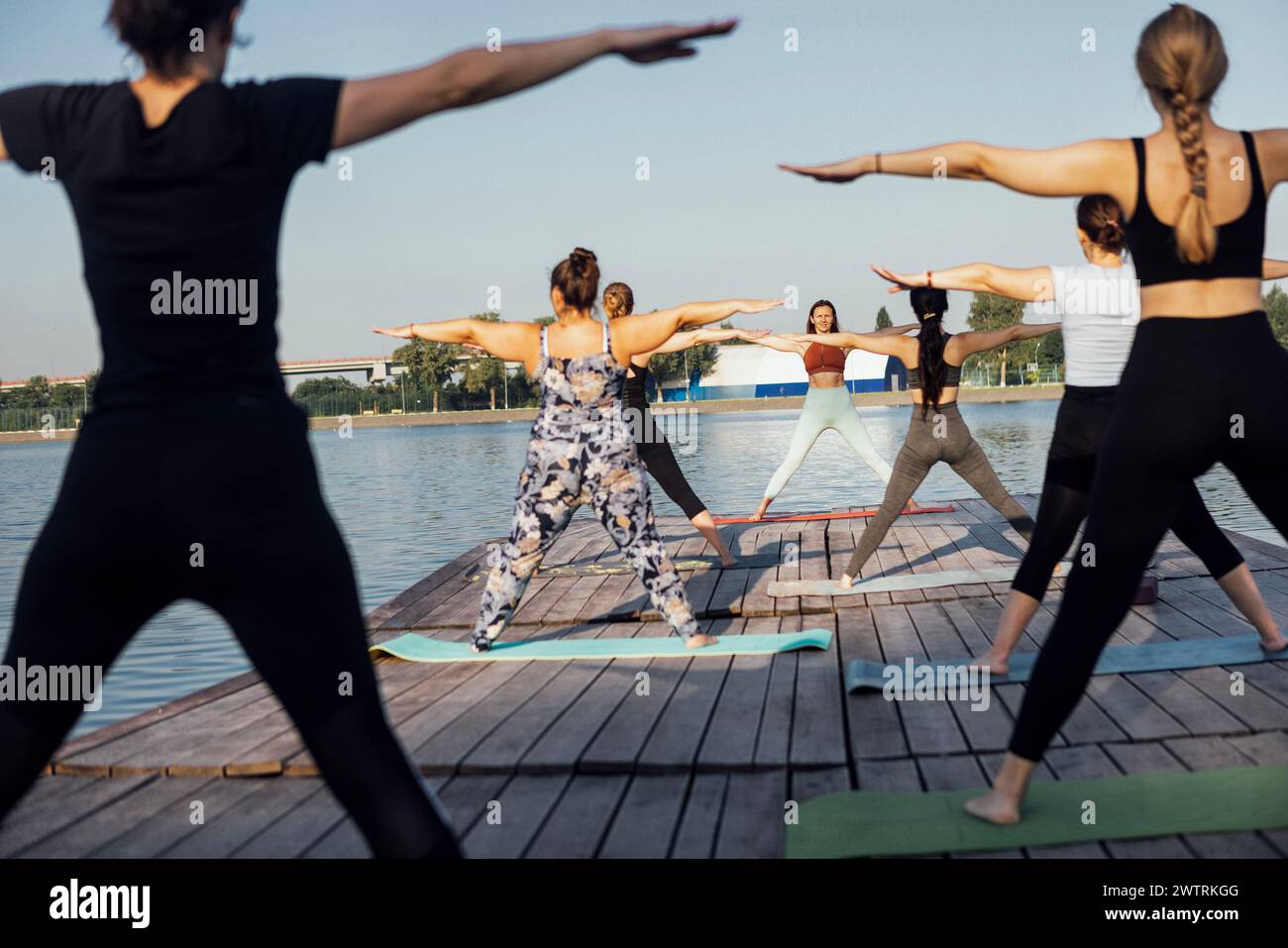 Morning yoga class outdoors with instructor near river in city. Young ...