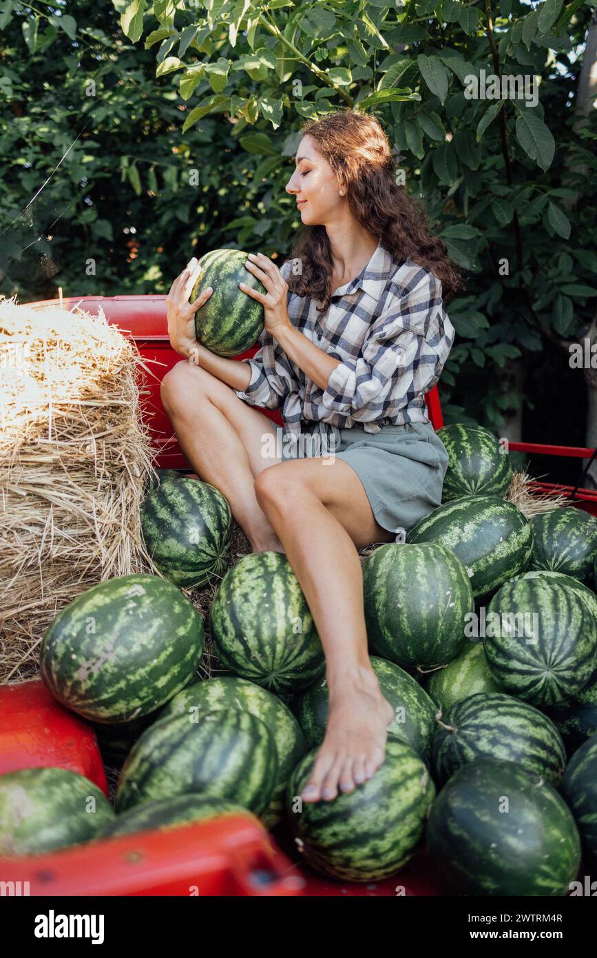 A charming smiling woman in casual clothes is sitting on a pile of ...