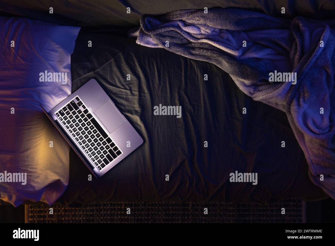 Laptop on the bed at night, light from the laptop screen, top view ...