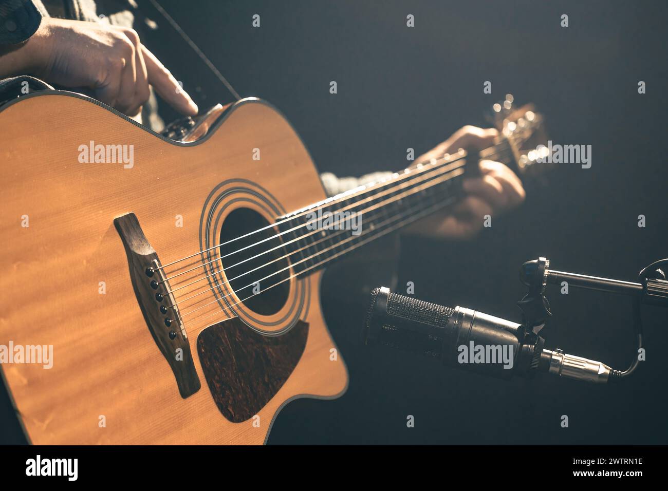 Male musician playing acoustic guitar behind microphone in recording ...