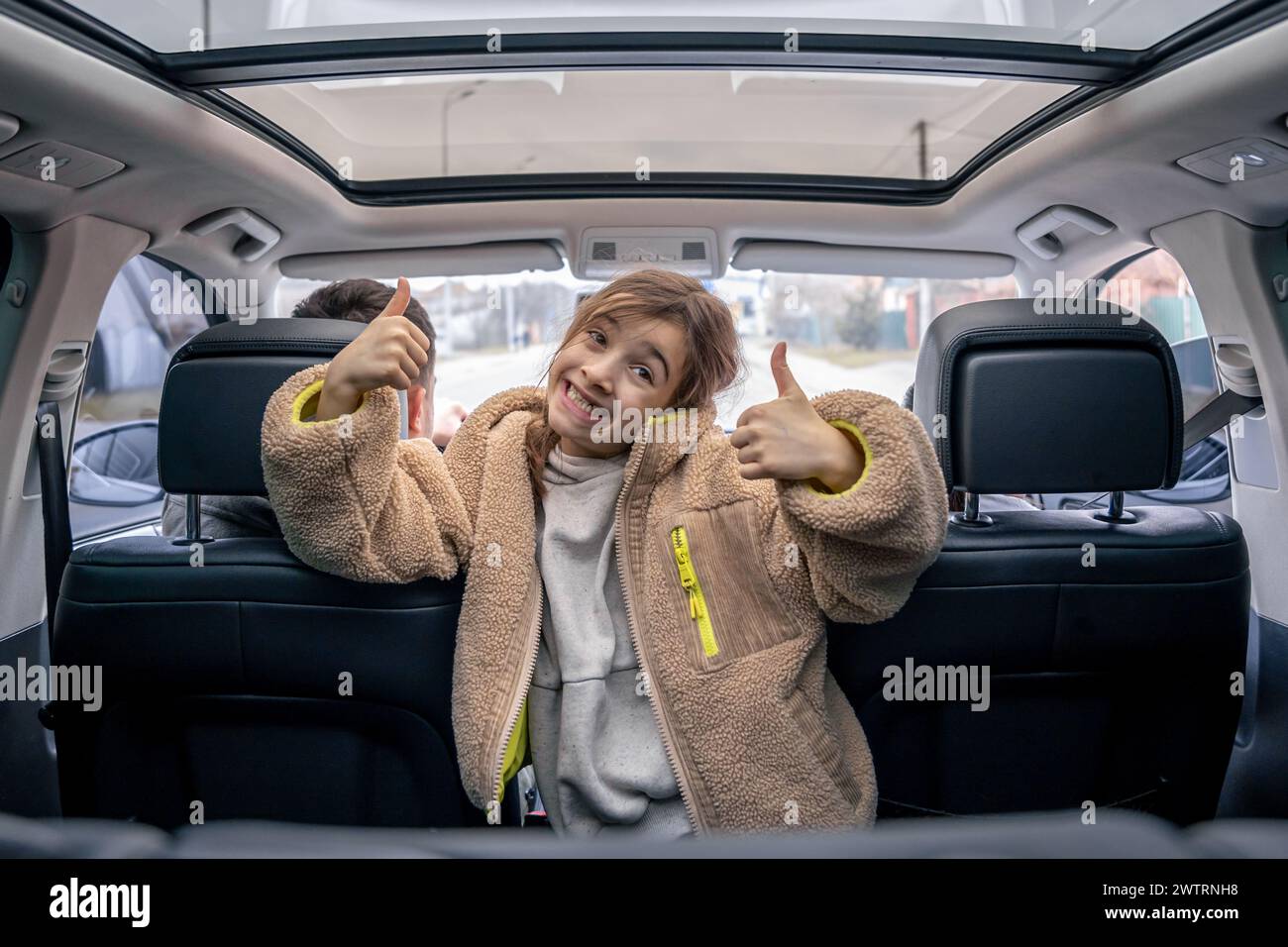 Little girl listens enjoys music and dancing in the car while family ...