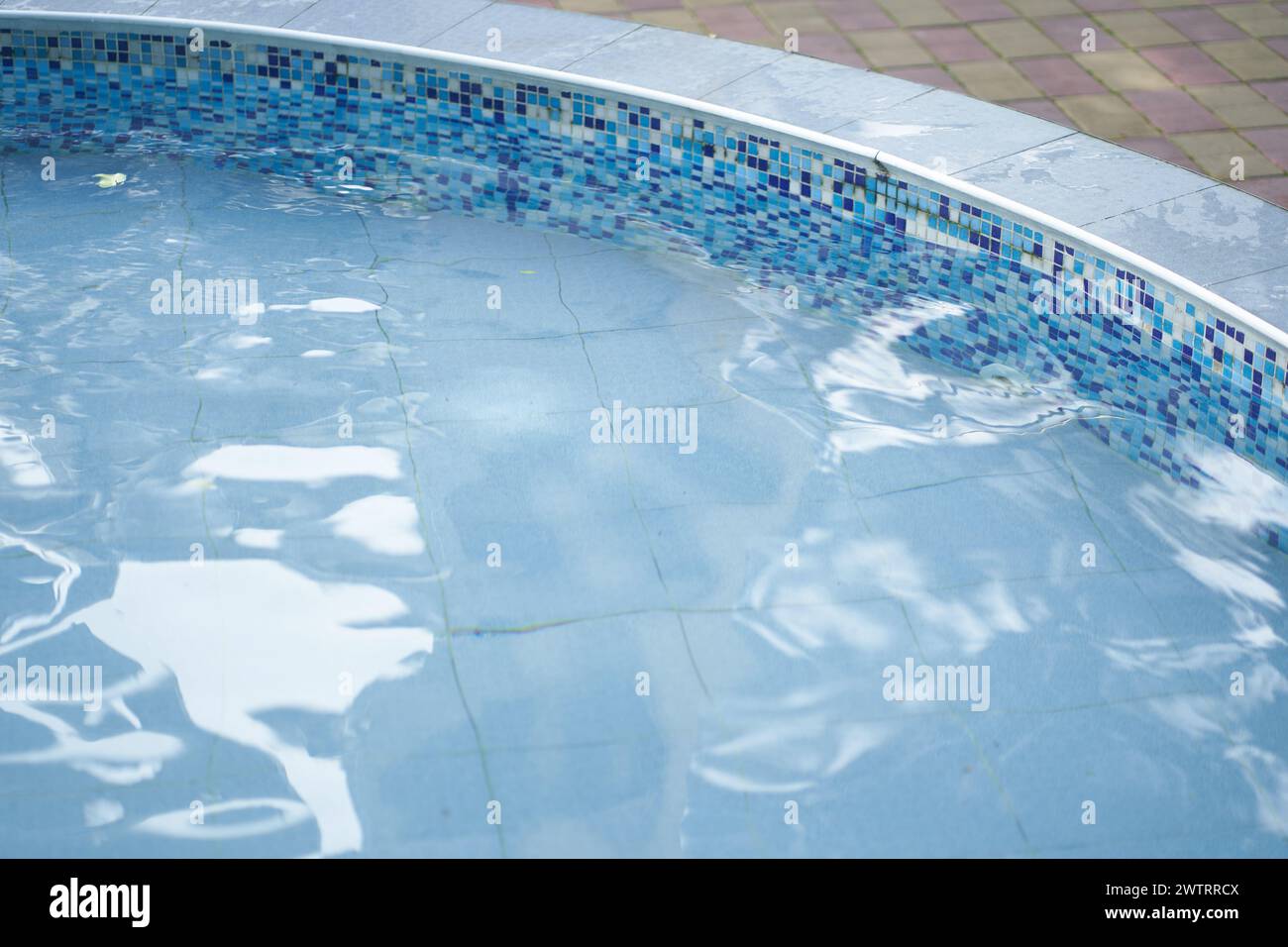 Cropped view of a round outdoor swimming pool with blue mosaic ceramic ...