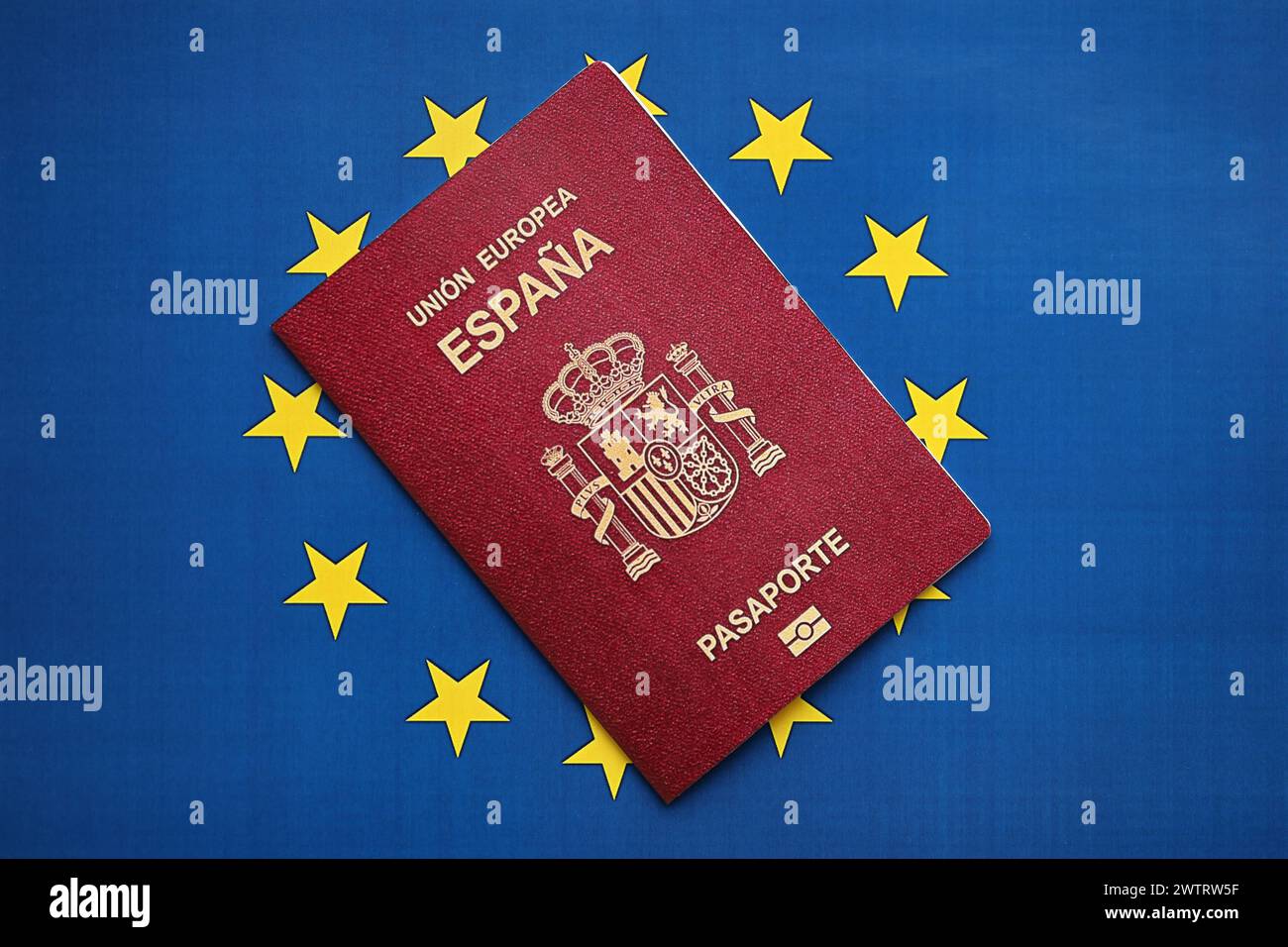 Red Spanish passport of European Union on blue flag background close up ...